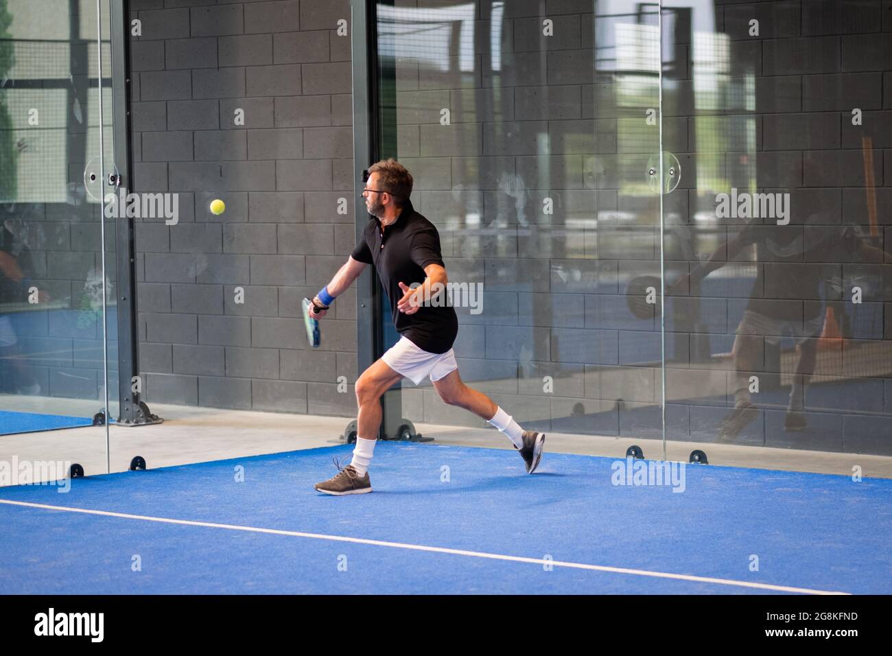 Man playing padel in a blue grass padel court indoor - Young sporty boy ...