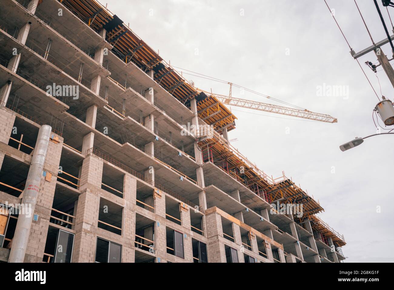 Low angle shot of a building in construction with a big crane wing in ...