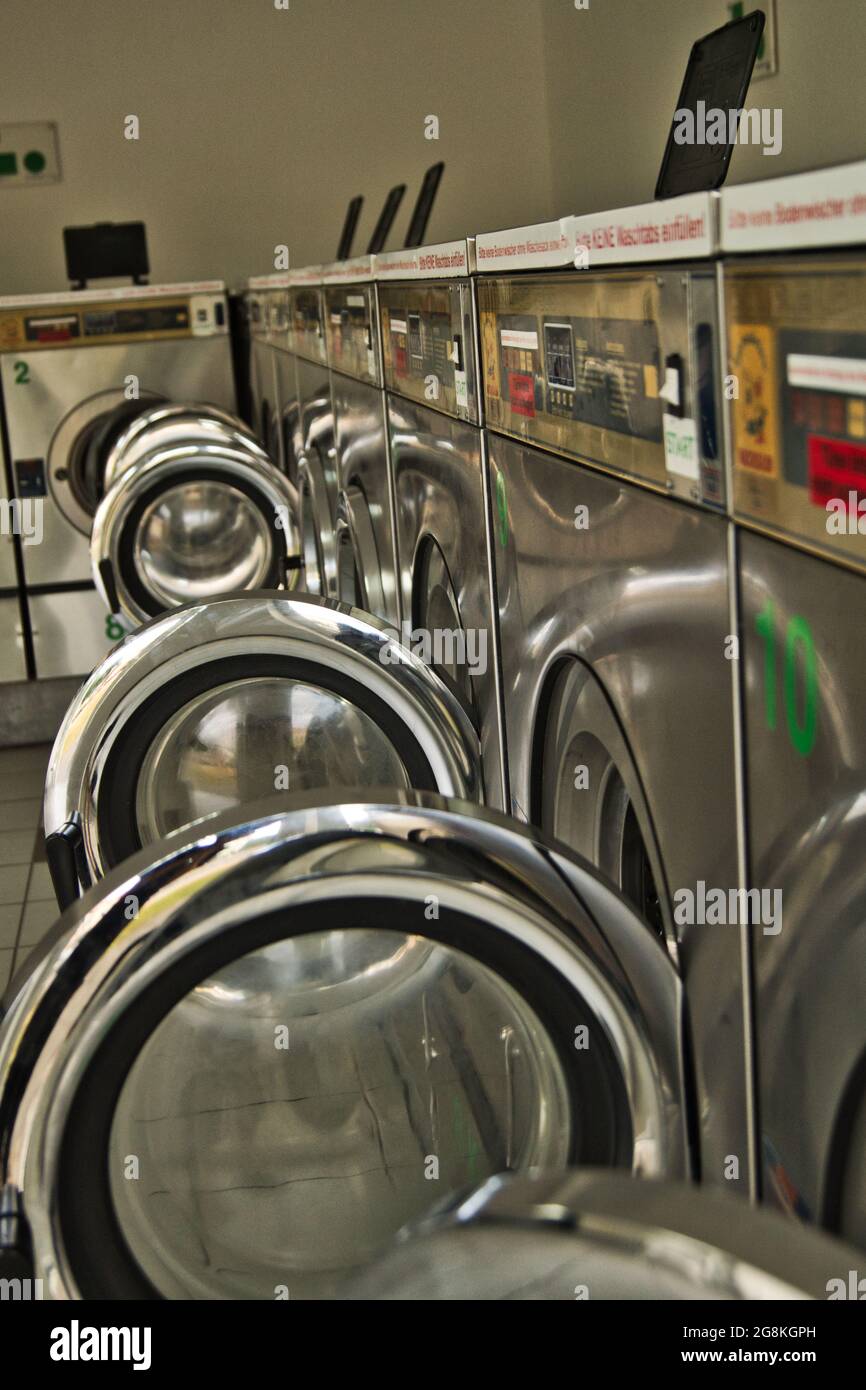 Vertical shot of silver washing machine with open doors in laundry ...