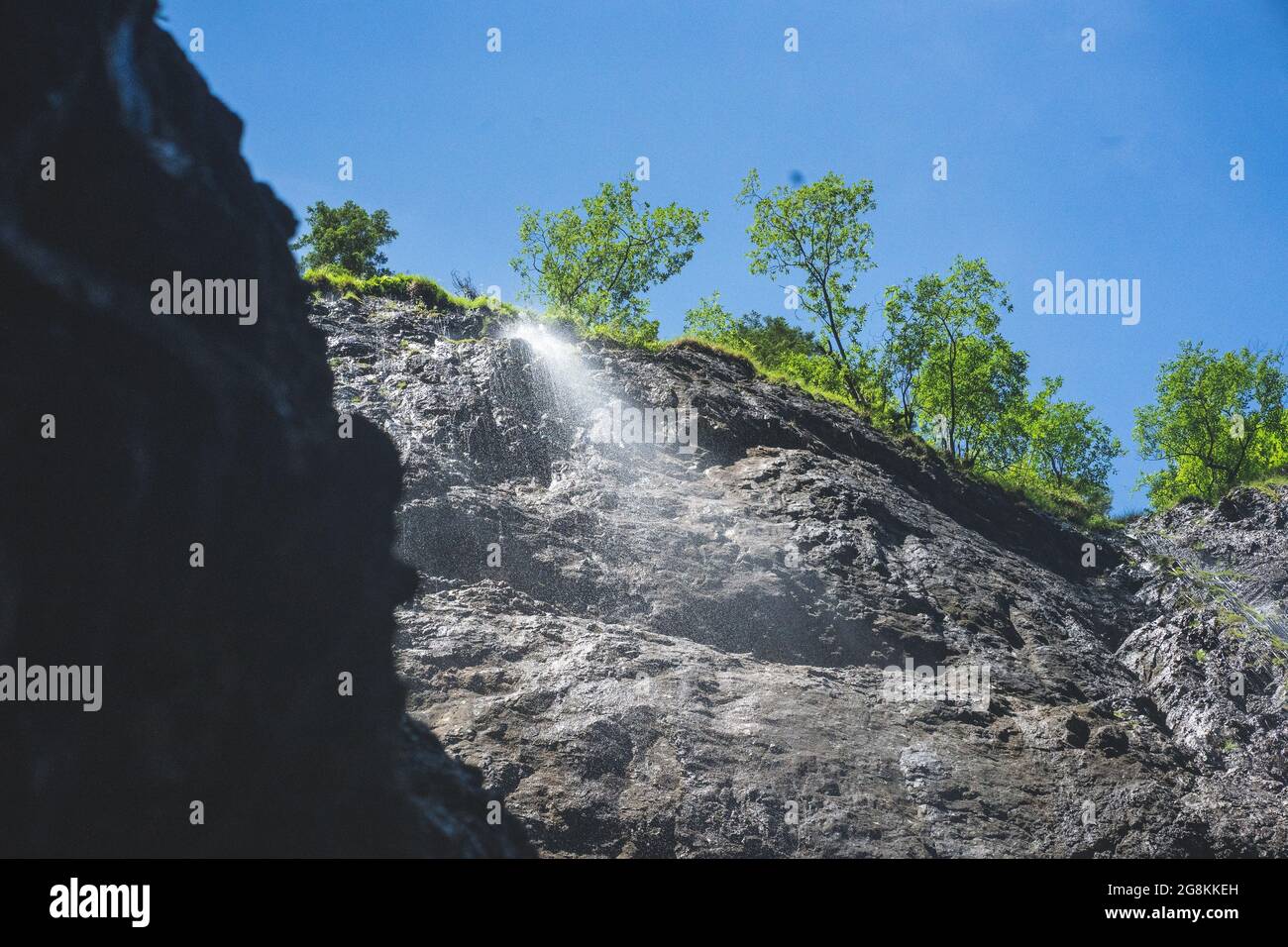 Low angle shot of a a small waterfall falling from a natural rock wall ...