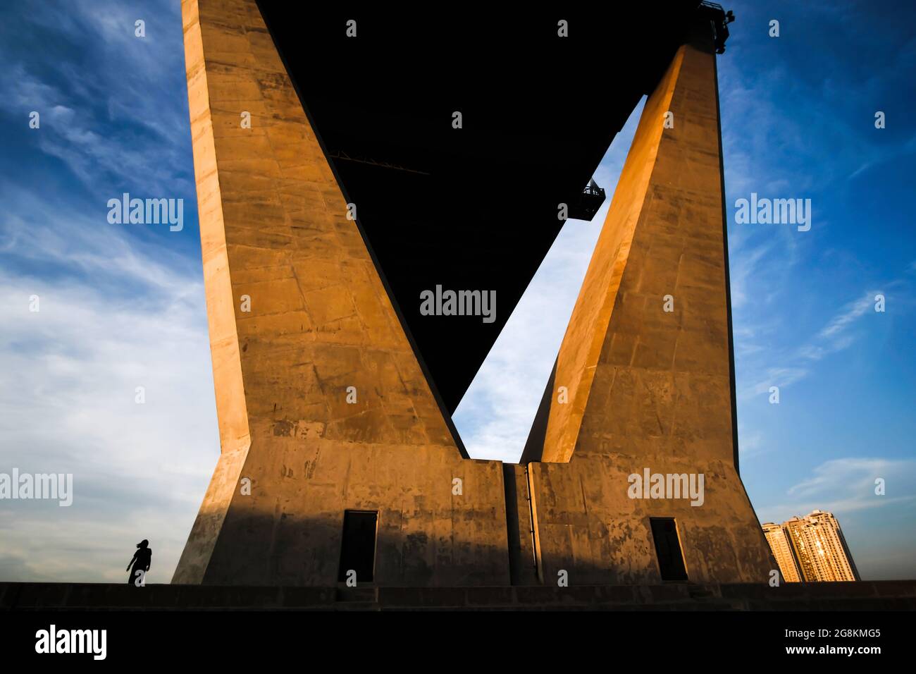 A female walks past the large two column bent of the suspension bridge ...