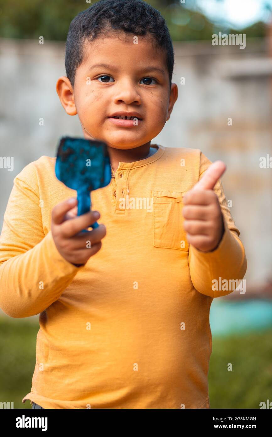 Closeup of a happy boy showing his plant sowing tool and thumbs up ...