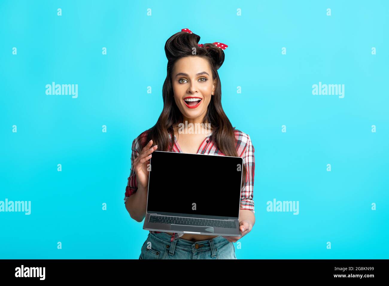 Smiling pinup woman in retro clothes showing laptop with empty screen ...