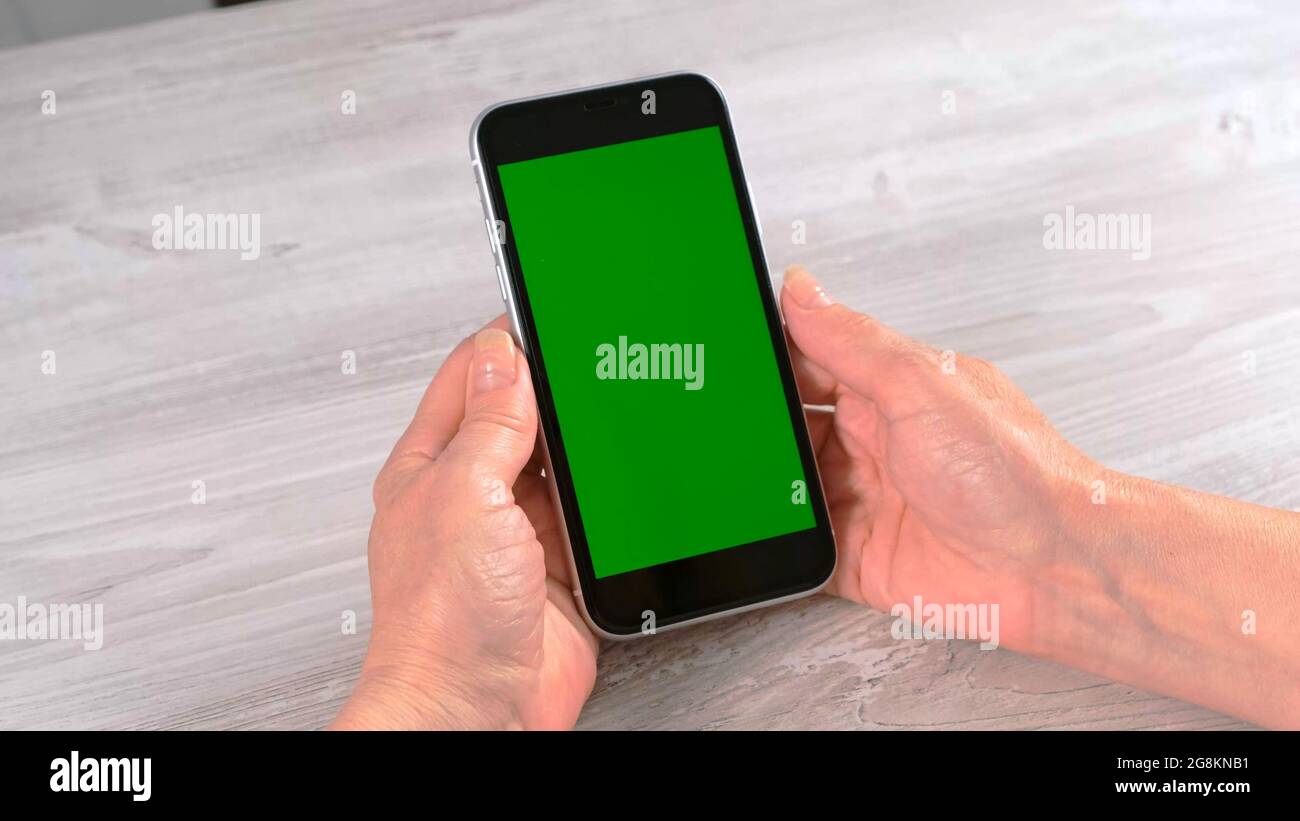 Hands of a middle-aged woman senior uses a smartphone iPhone with a ...