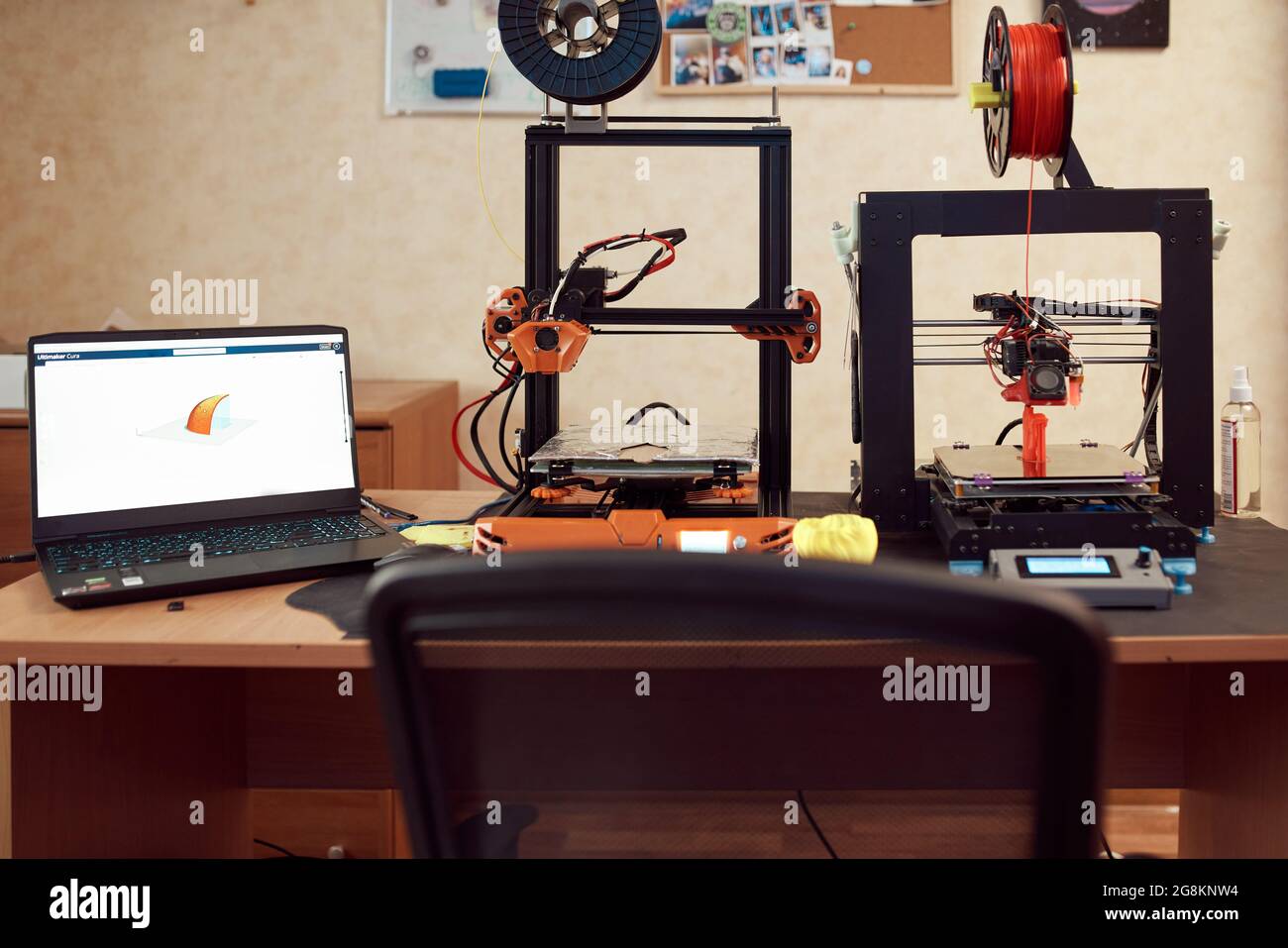 Table with modern netbook and 3D printers located near chair in ...
