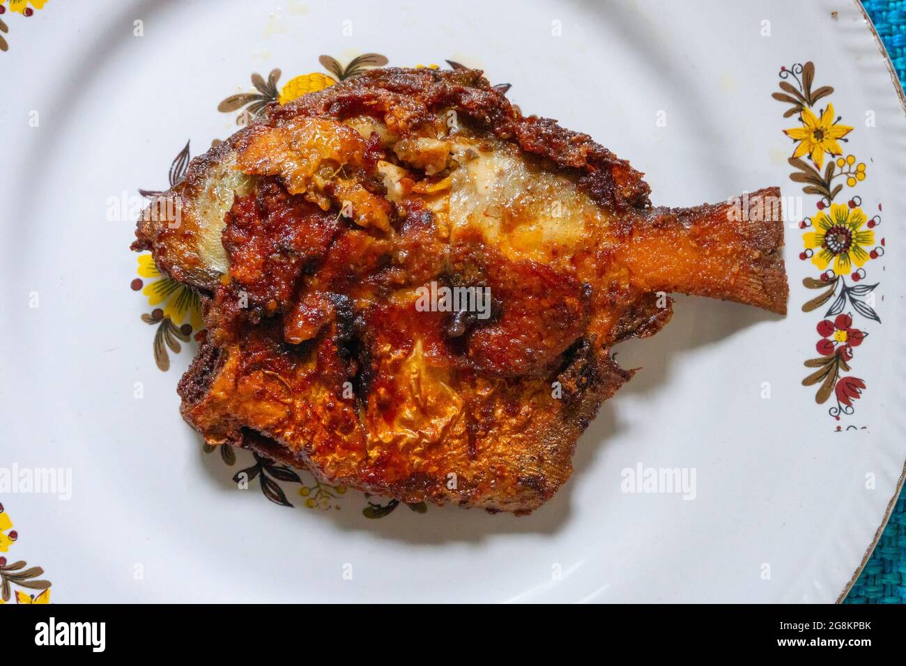 A fried pomfret fish served on a white decorated platter, Spicy Indian ...