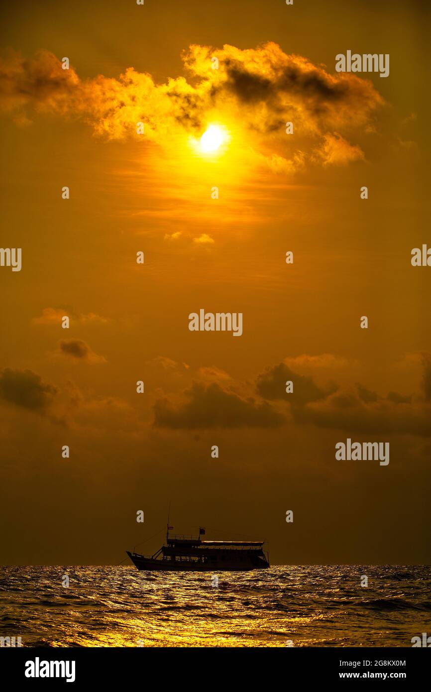 Boat on texture of tropical sea water and wave in golden light of ...