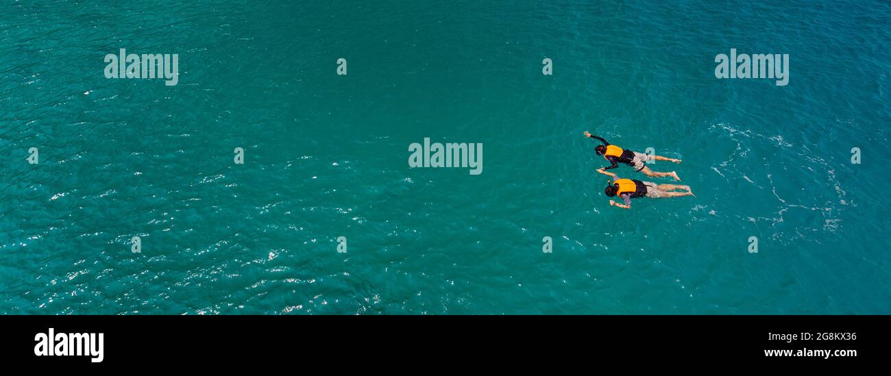 Couple catch each other hands and swim, skin diving to sea reef in ...