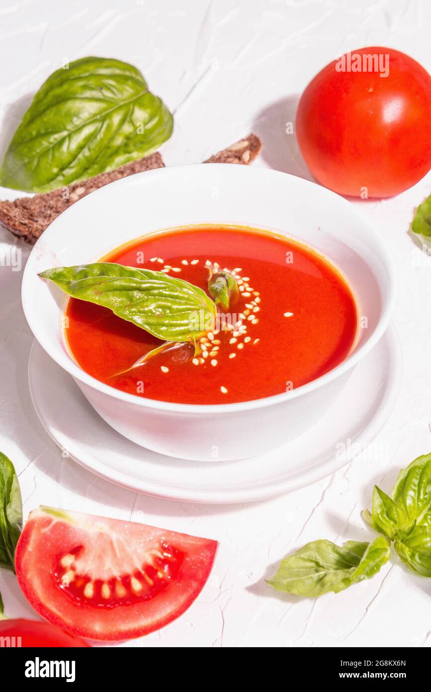 Bowls with homemade tomato soup. Ripe vegetables, fresh basil leaves ...
