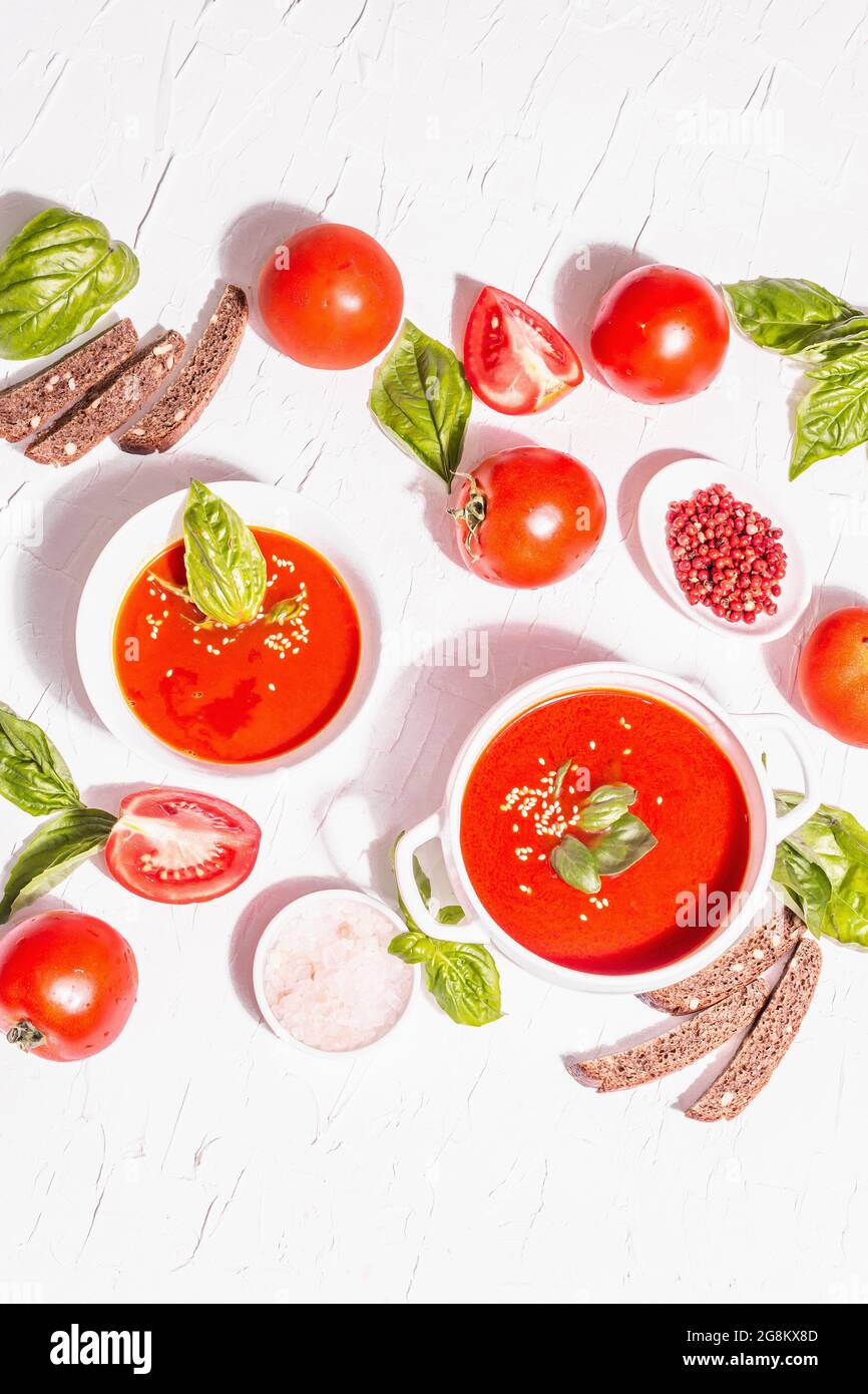 Bowls with homemade tomato soup. Ripe vegetables, fresh basil leaves ...
