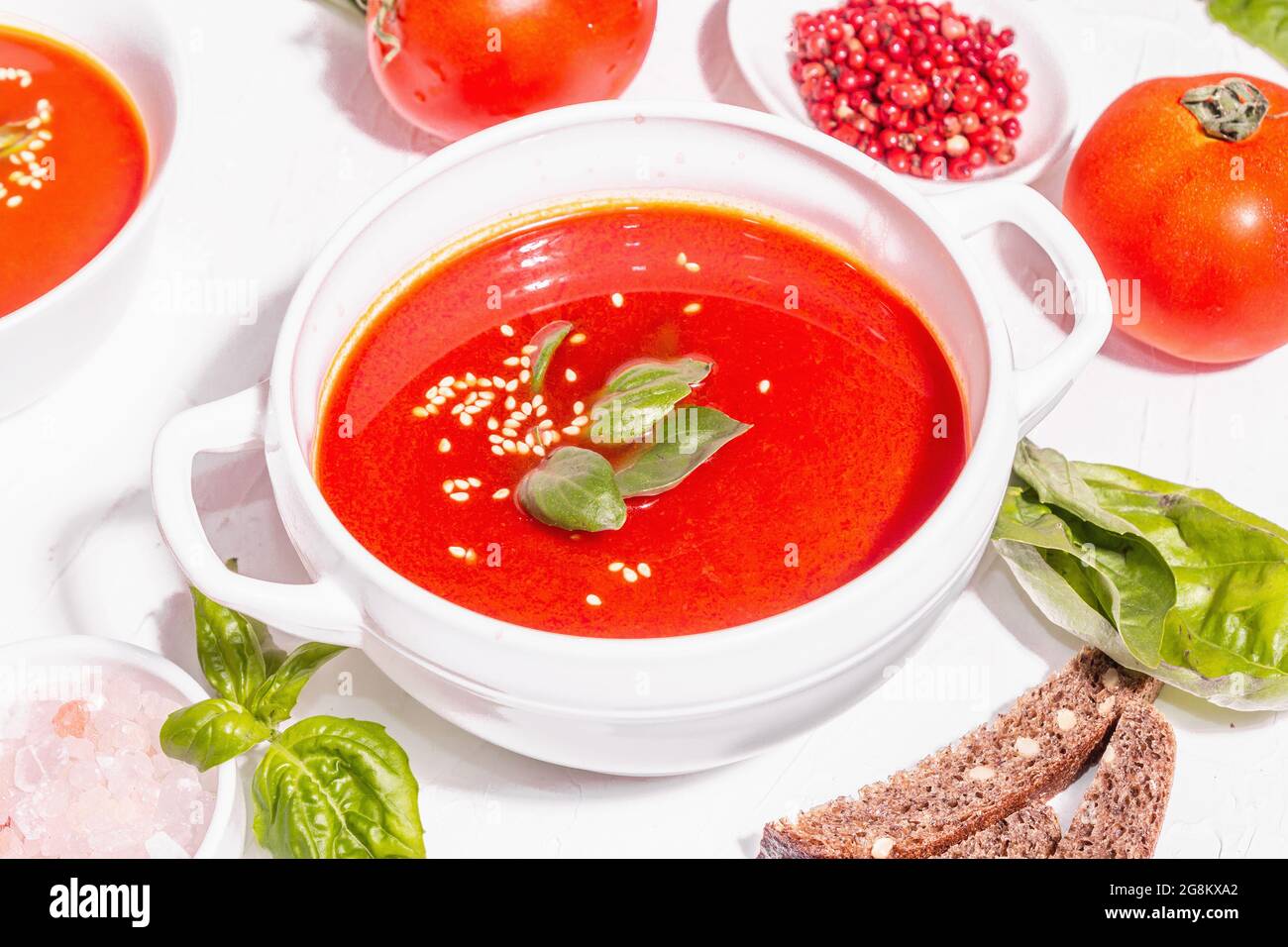Bowls with homemade tomato soup. Ripe vegetables, fresh basil leaves ...