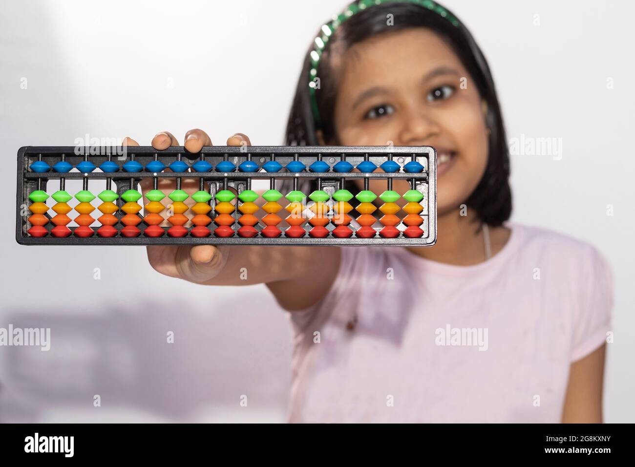 Selective focus on abacus shown by an Indian girl child on white ...
