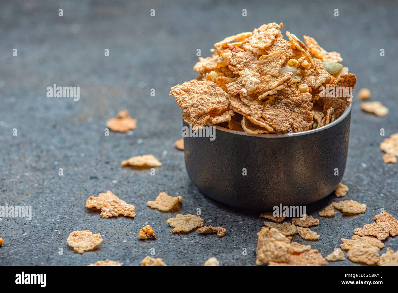 Dry muesli in a saucer on the background of a stone table top. Healthy ...