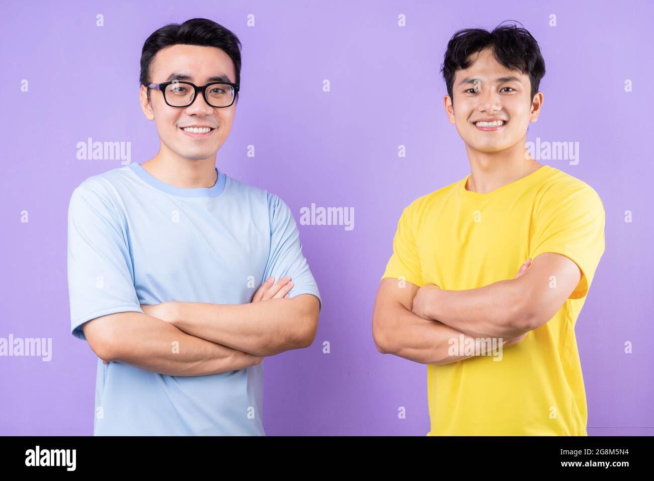 Young Vietnamese friends with crossed arms happily posi on vibrant ...