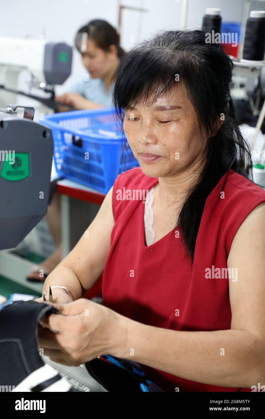 A factory worker is sewing cloth at a textile factory in Zixing city ...