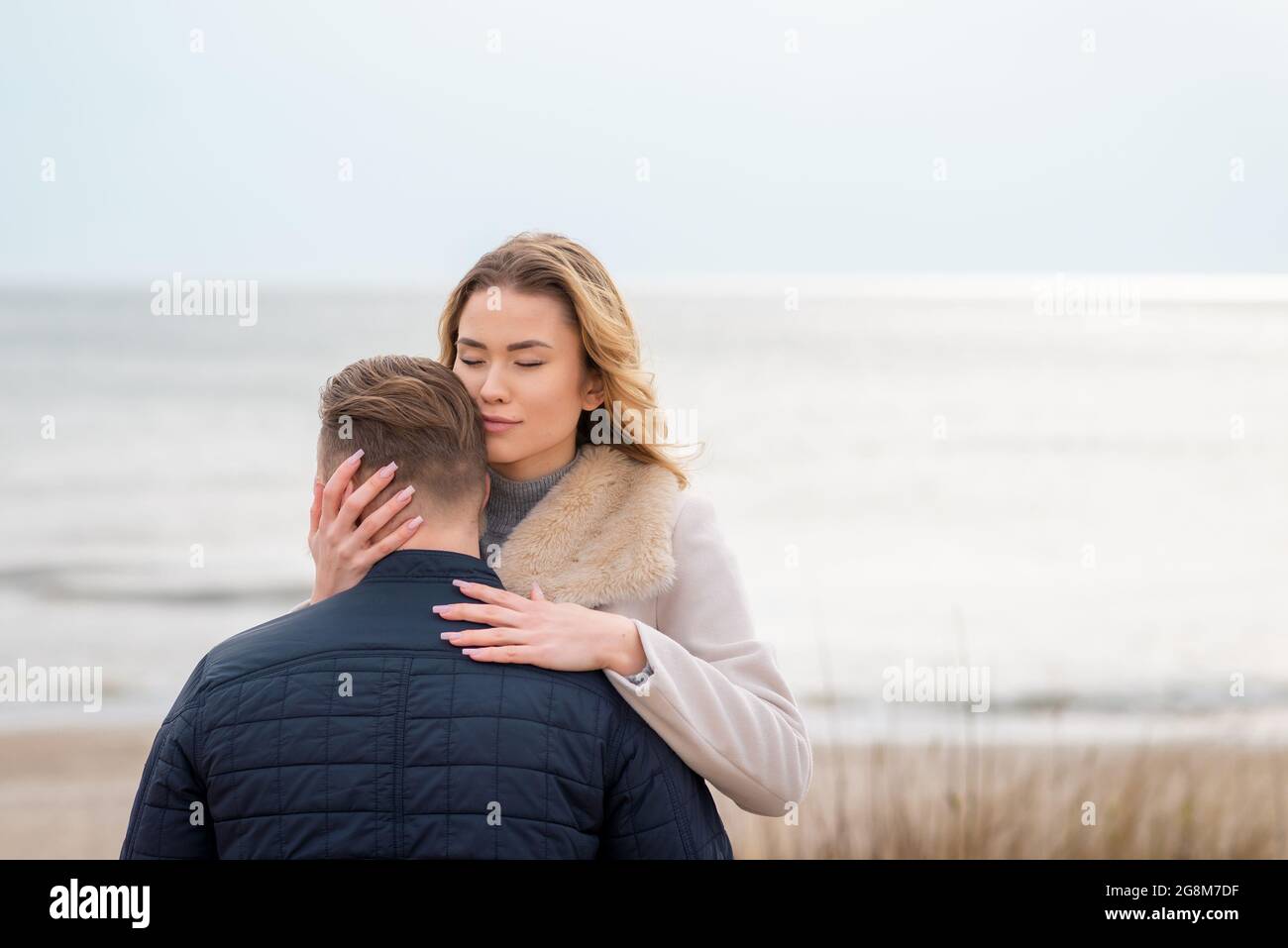 young beautiful stylish couple in spring on the beach. Hug each other ...