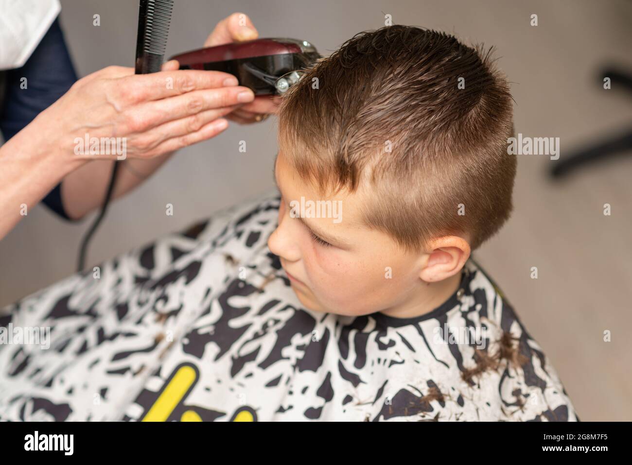 Cute kid boy have hair cut, professional barber doing haircut ...