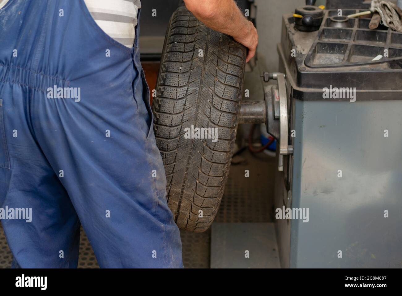 Car mechanic balancing car wheel,tire on a computer machine balancer in ...