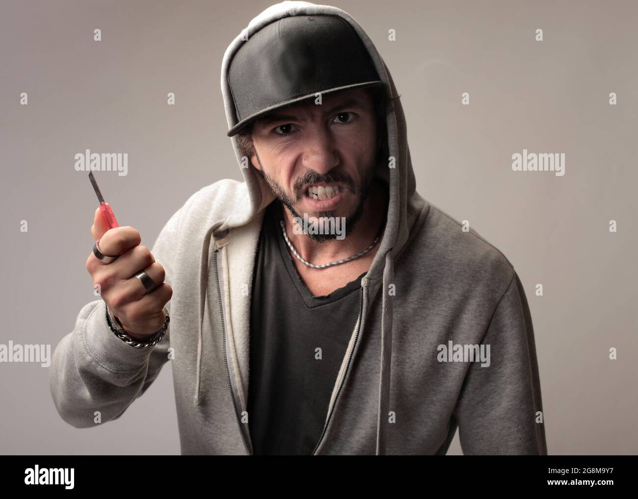 Adult male criminal wearing a cap with a jacket and threatening with a ...