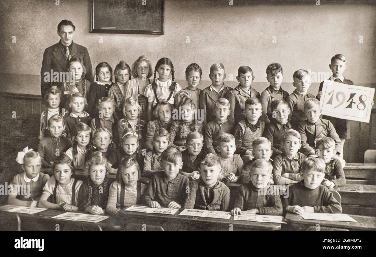 Children and teacher in the classroom. Retro picture of classmates in ...