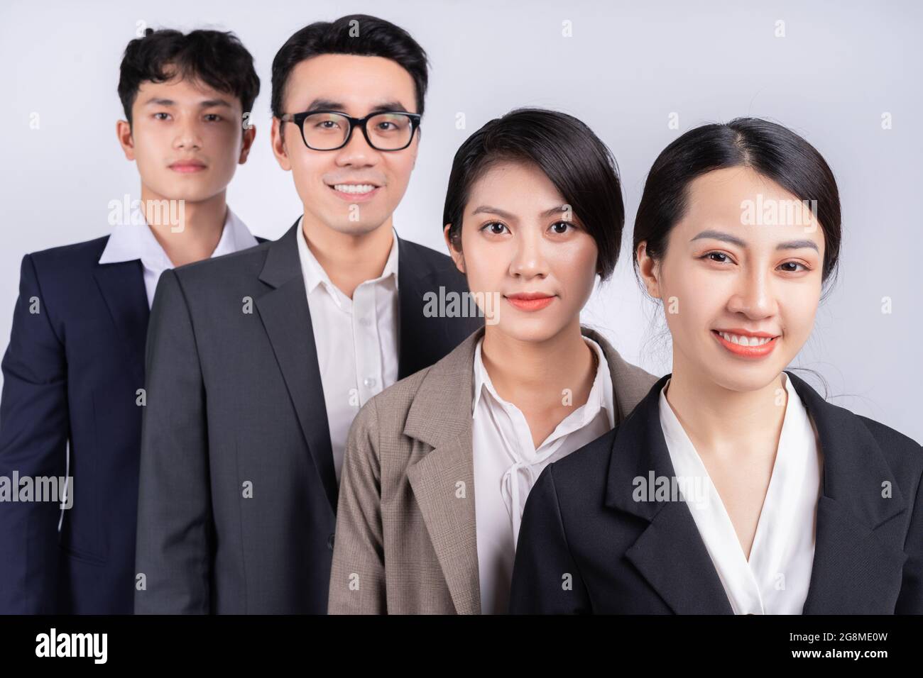 Young Vietnamese business team in suits happily posing on background of ...