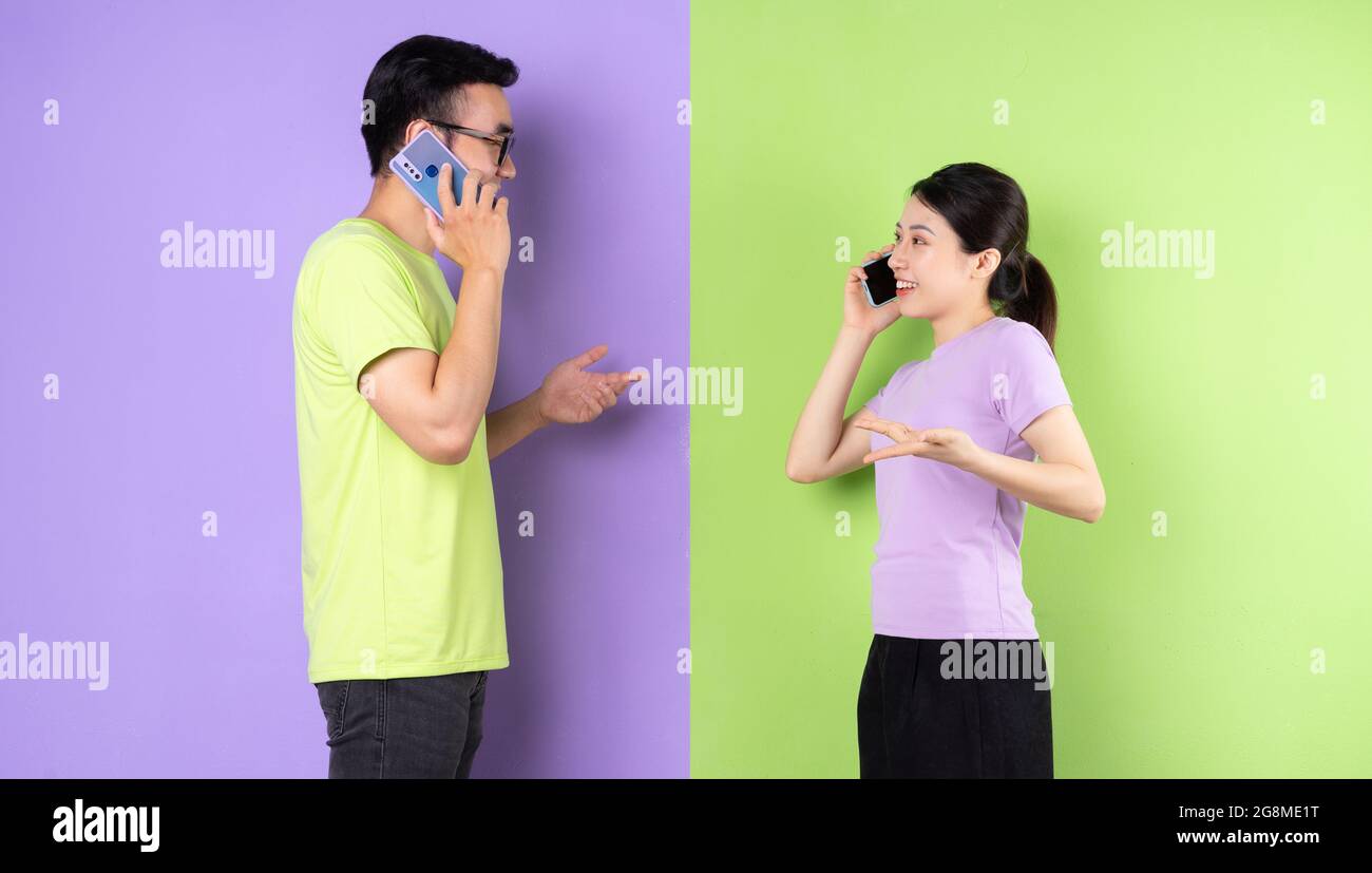 Young Vietnamese people talking on the phone on green and purple split ...