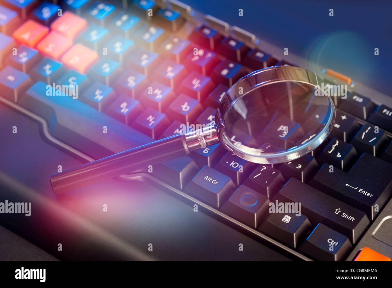 Magnifying glass on laptop keyboard in neon light Stock Photo - Alamy