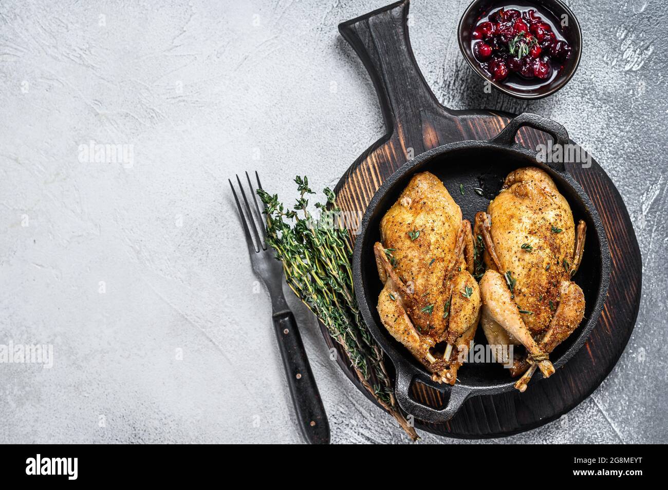Whole roast quails in a pan. White background. Top view. Copy space ...