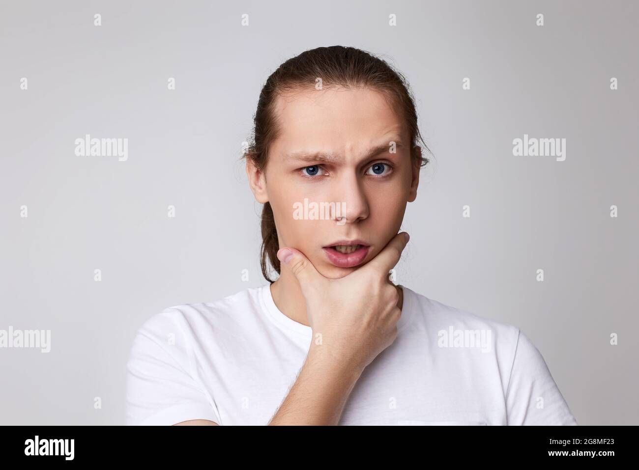 young handsome man touch his chin by hand thinking Stock Photo - Alamy