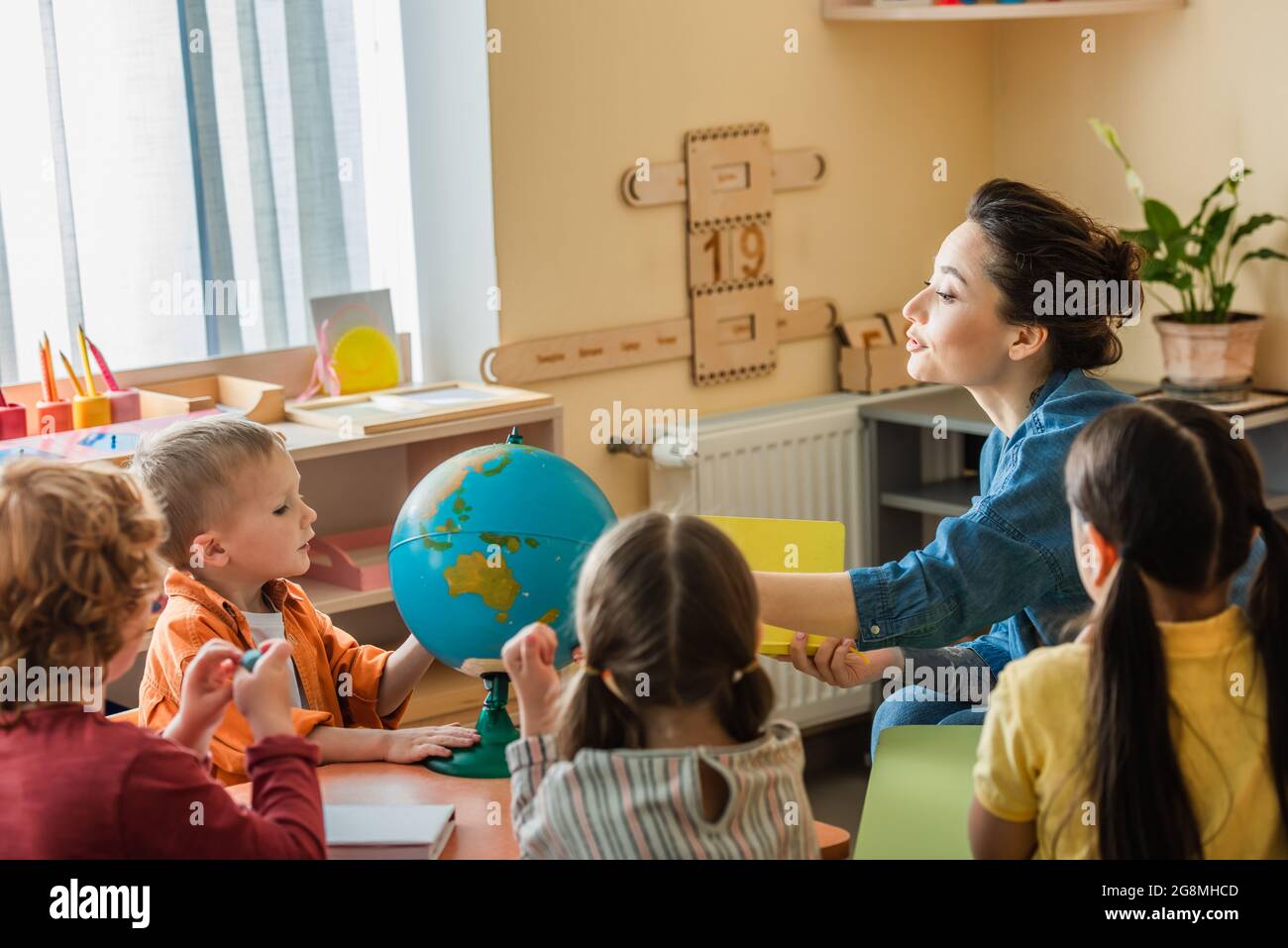 young teacher talking to children near globe during lesson Stock Photo ...