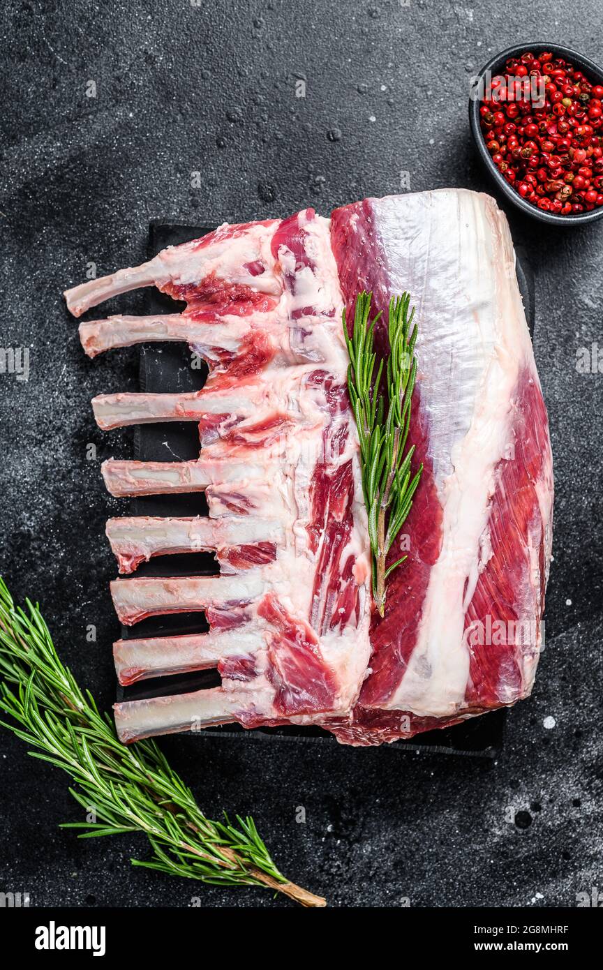 Raw fresh rack of lamb meat on marble board. Black background. Top view ...