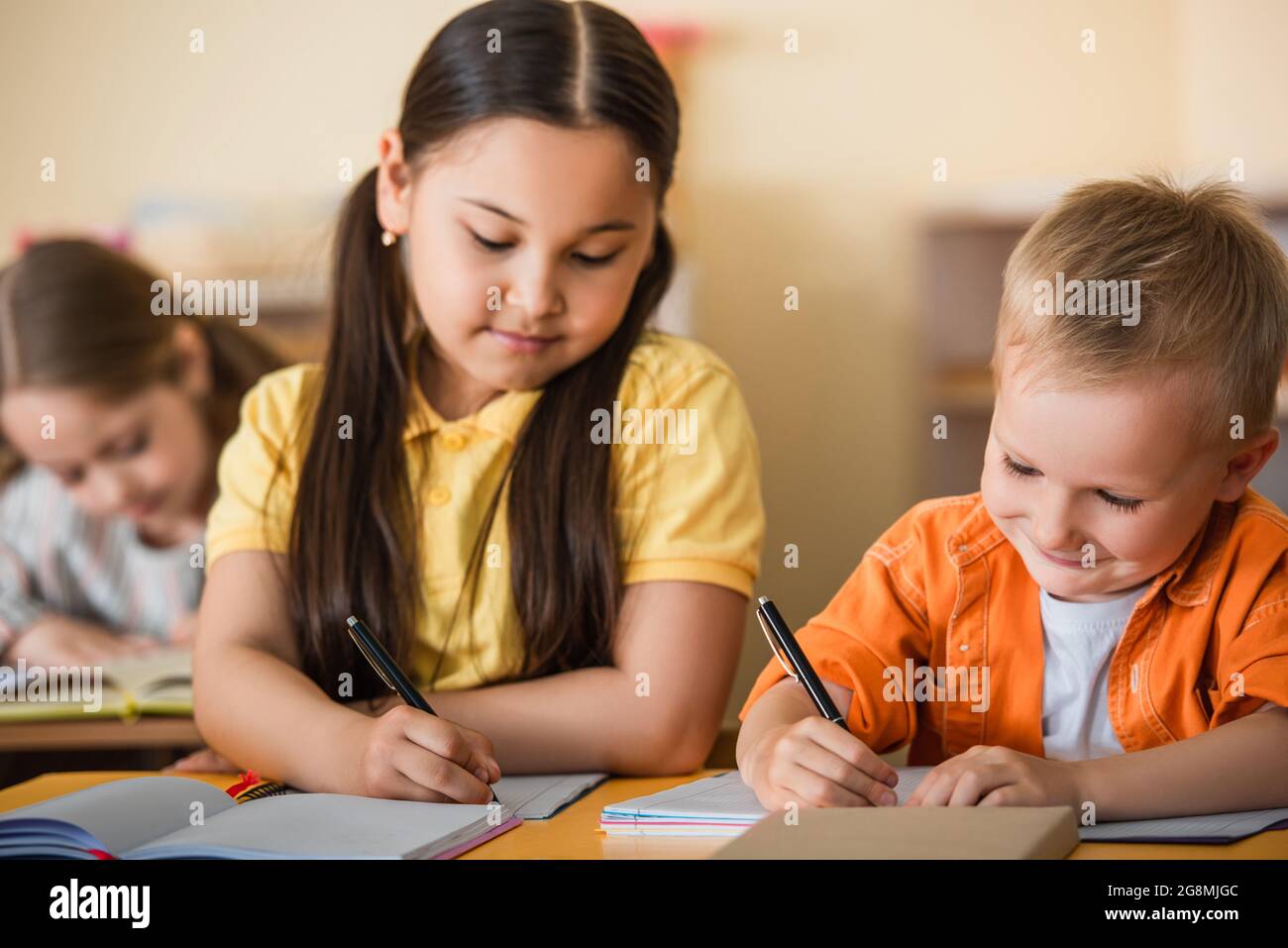 multiethnic children writing in copy books during lesson in montessori ...