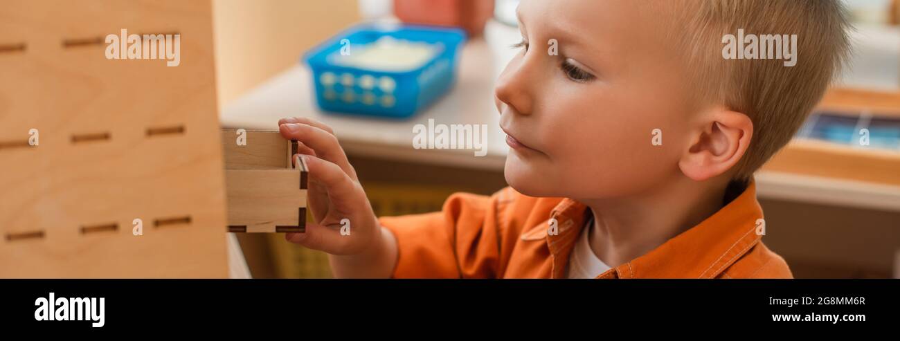 kid opening cabinet in wooden box during learning in montessori school ...
