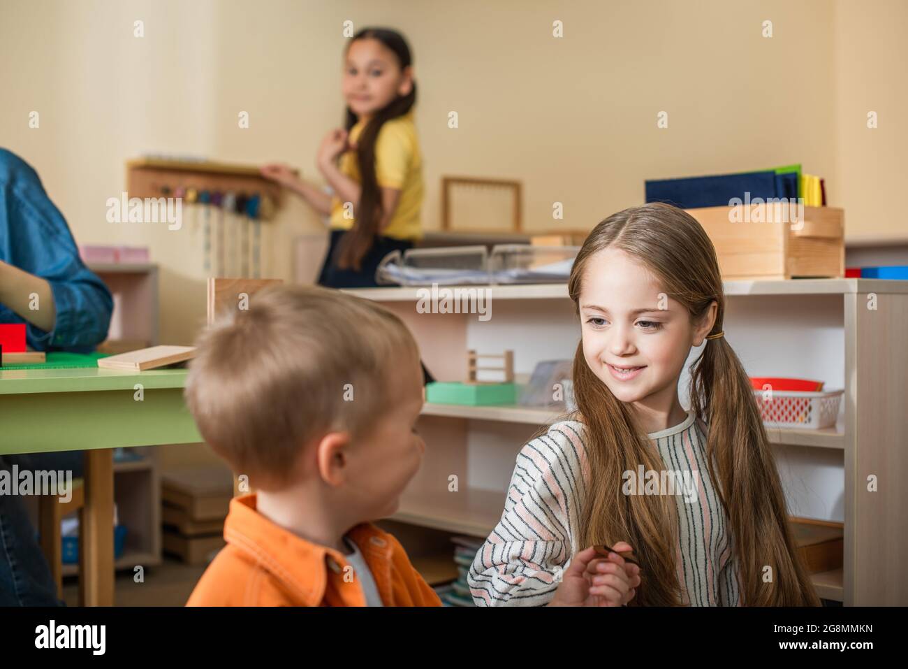 children talking in classroom near teacher and asian girl on blurred ...