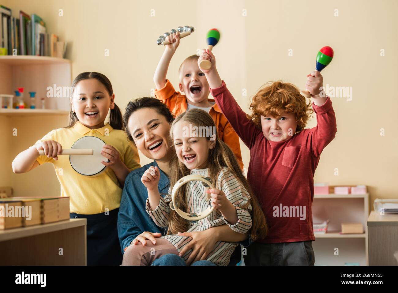 excited multiethnic kids playing musical instruments near happy teacher ...