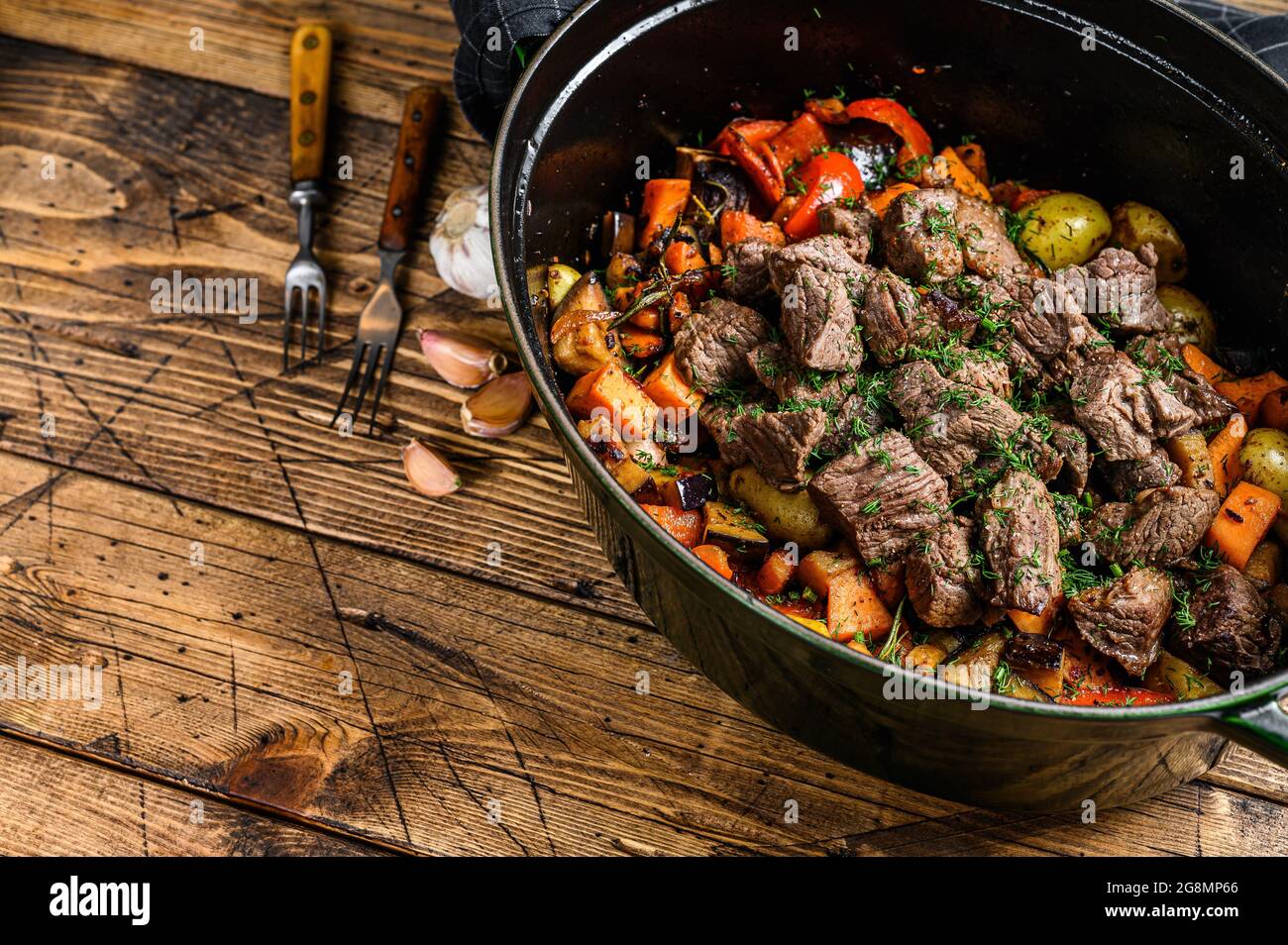 Beef meat and vegetables stew in black baking dish. Wooden background ...