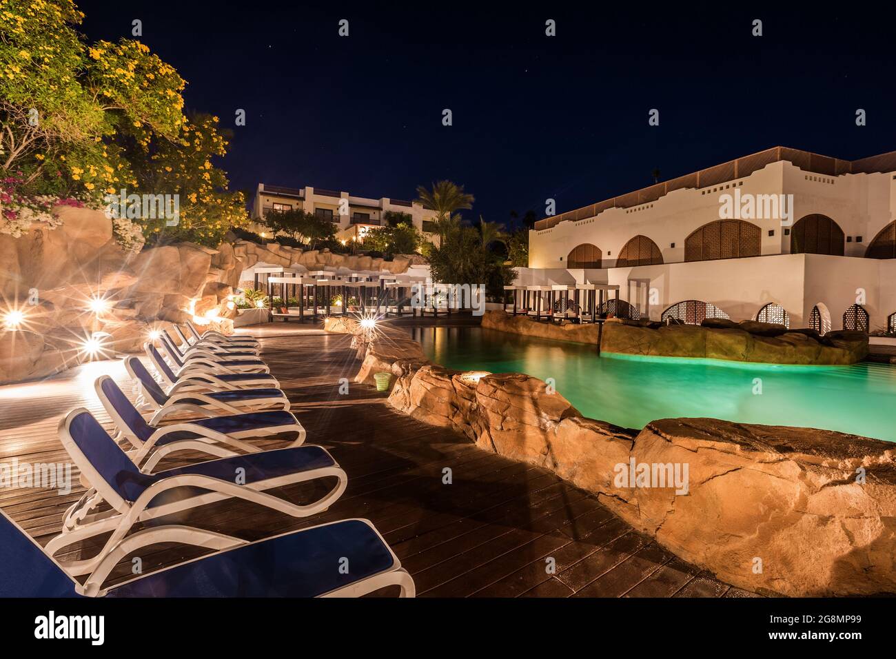 Swimming pool at night illumination and luxury buildings behind it ...