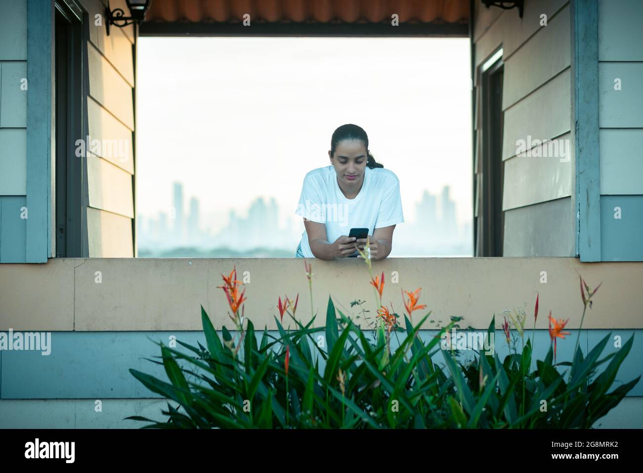 Happy young Hispanic female sending a text message on her cell phone ...