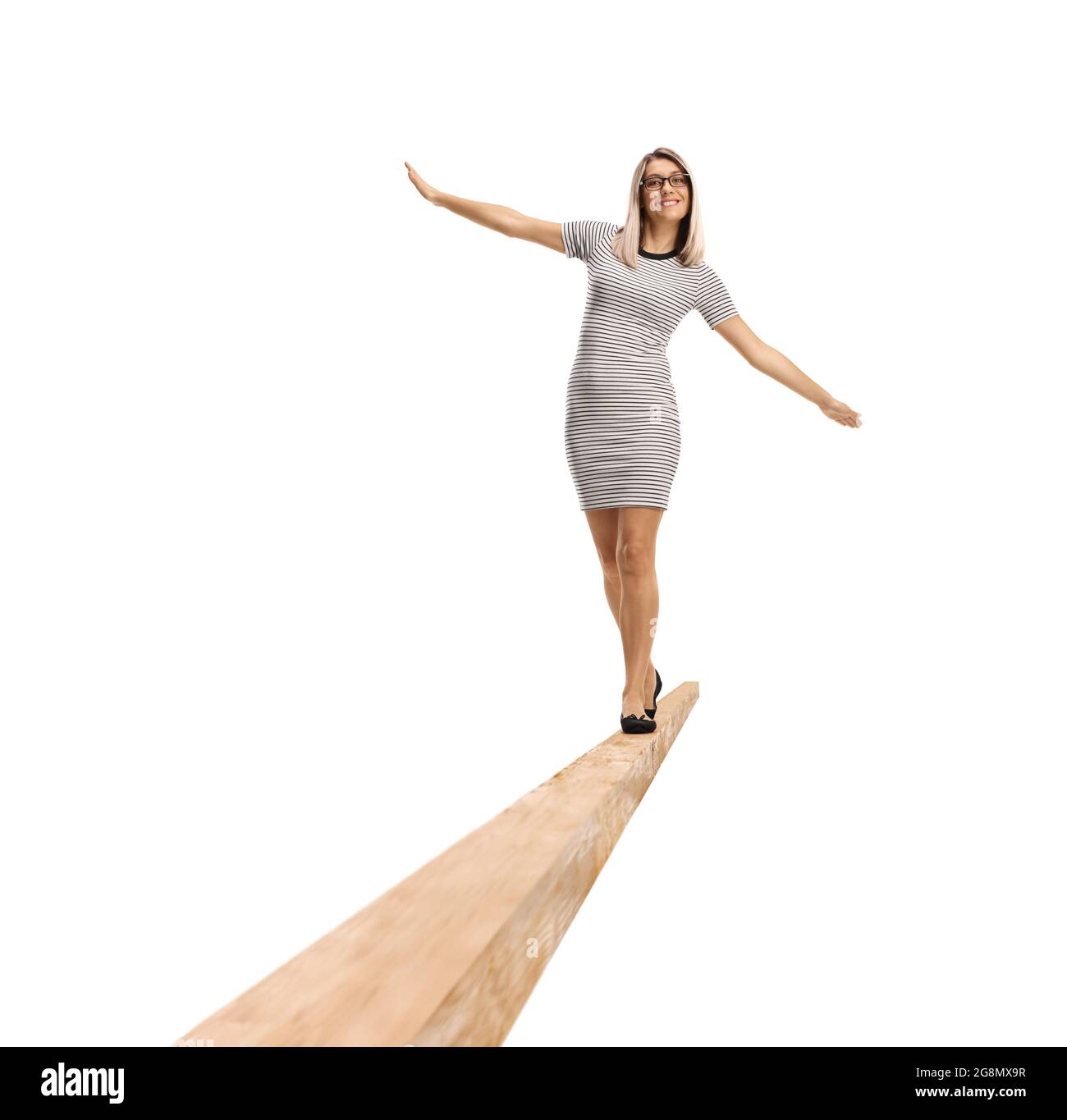 Full length portrait of a young woman walking on a wooden beam isolated ...