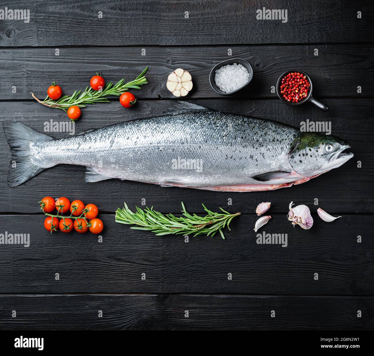 Fresh rainbow trout on black wooden surface, top view with space for ...