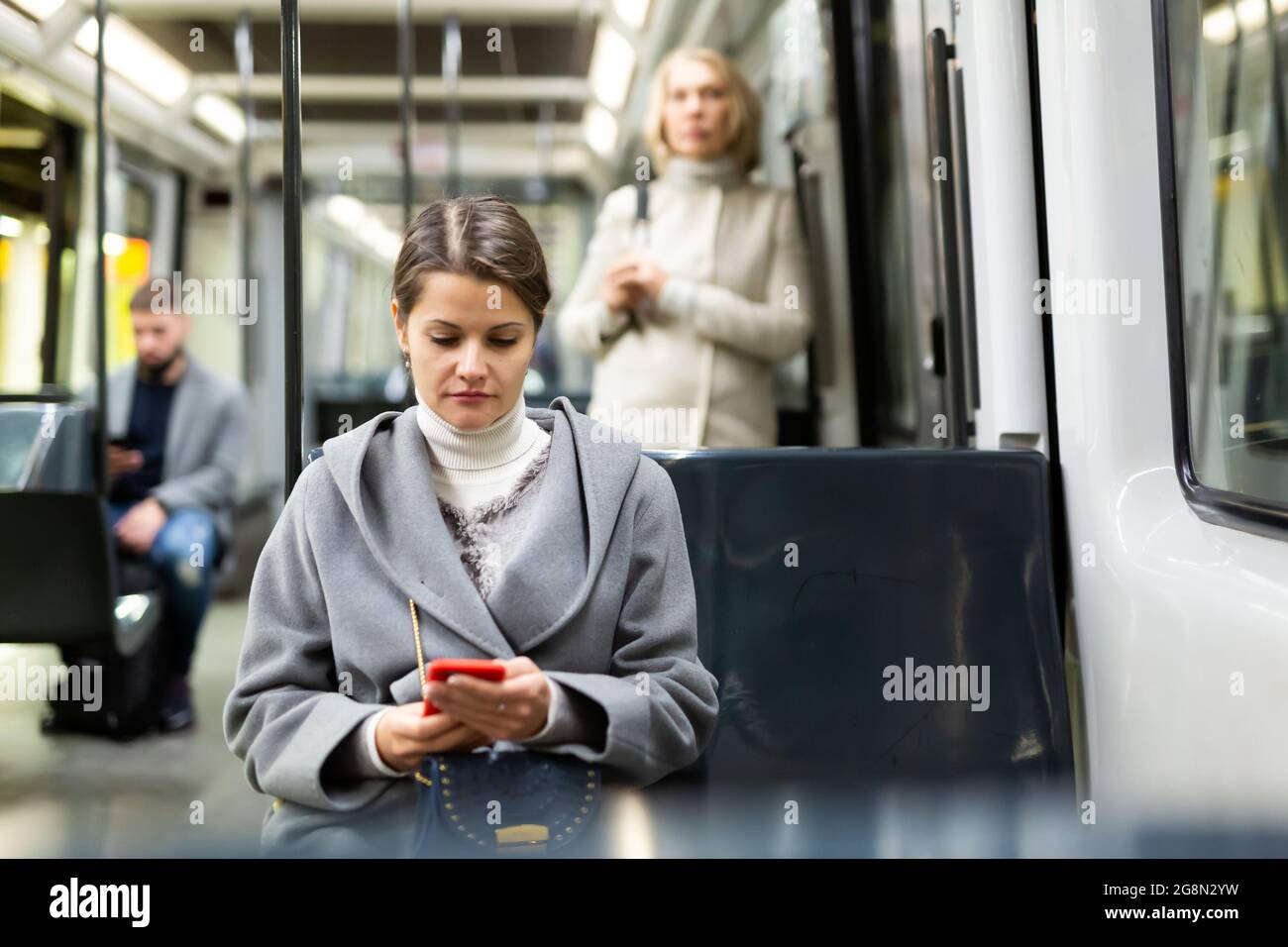 Positive woman reading from mobile phone screen in tram Stock Photo - Alamy