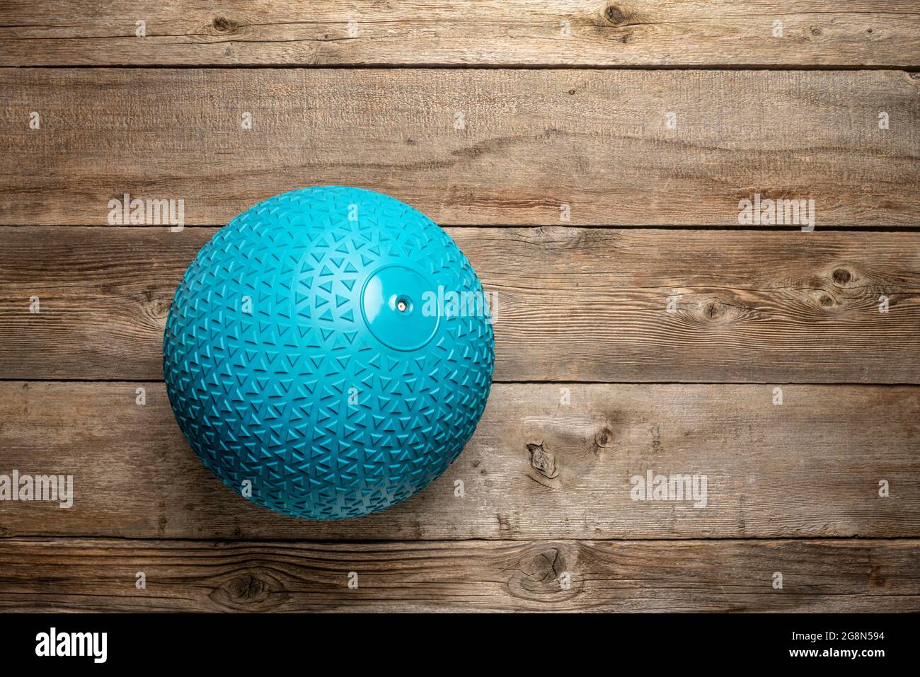 heavy rubber slam ball filled with sand on a rustic wooden deck ...
