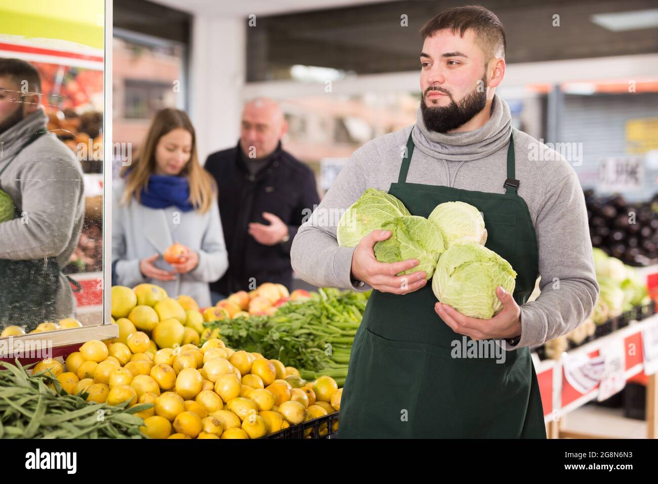 Male shop assistant lays fresh cabbage on counter in grocery shop Stock ...