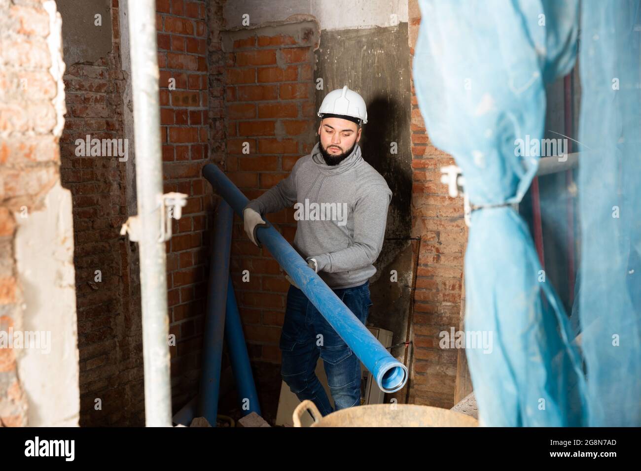 Guy working with plastic pipes at building site Stock Photo - Alamy