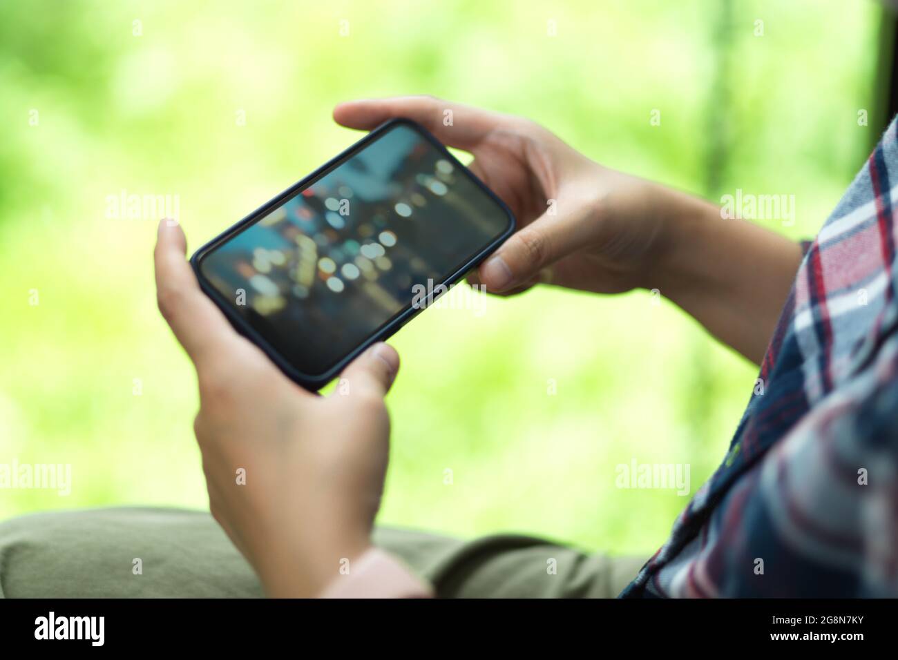 Male chilling and watching video via smartphone at park, phone mock up ...