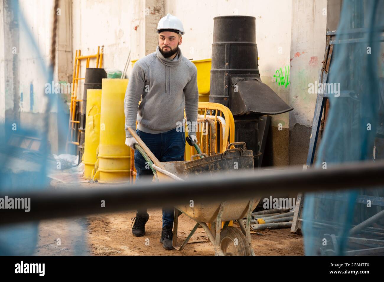 Worker carrying bucket with cement mortar on cart Stock Photo - Alamy