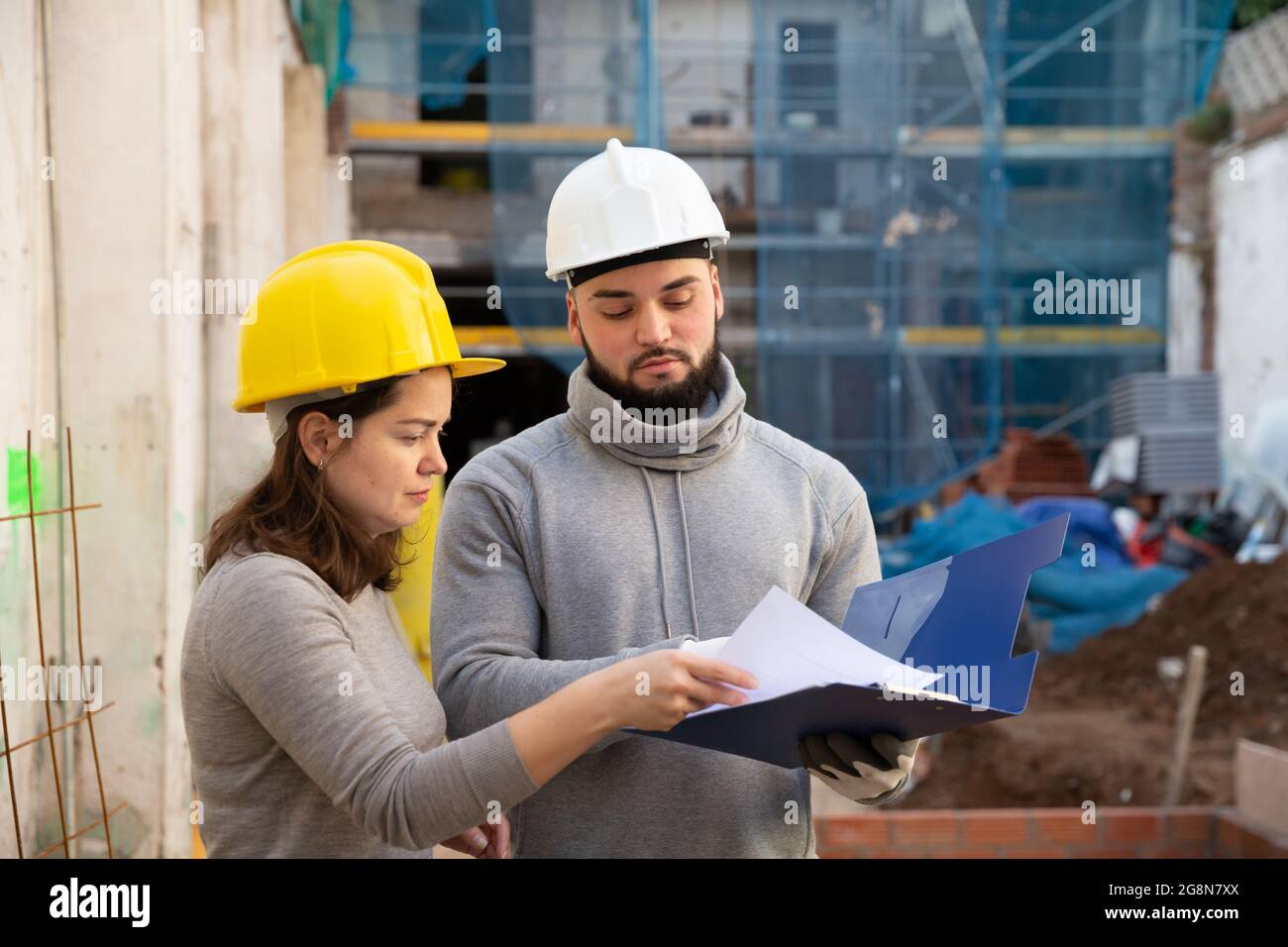 Engineers discussing blueprint at construction site Stock Photo - Alamy