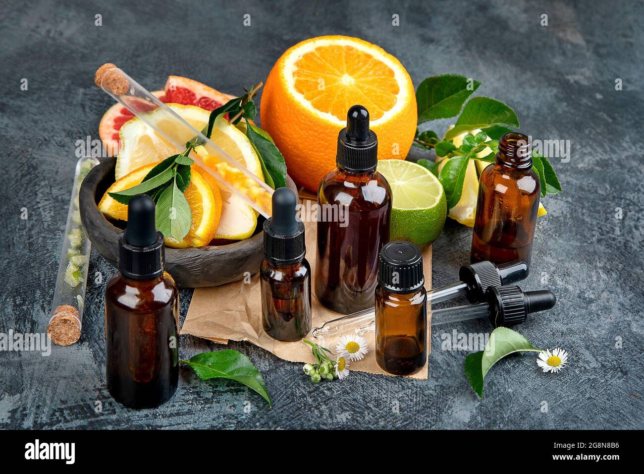 Bottles of essential aroma oils with citrus on dark gray background ...
