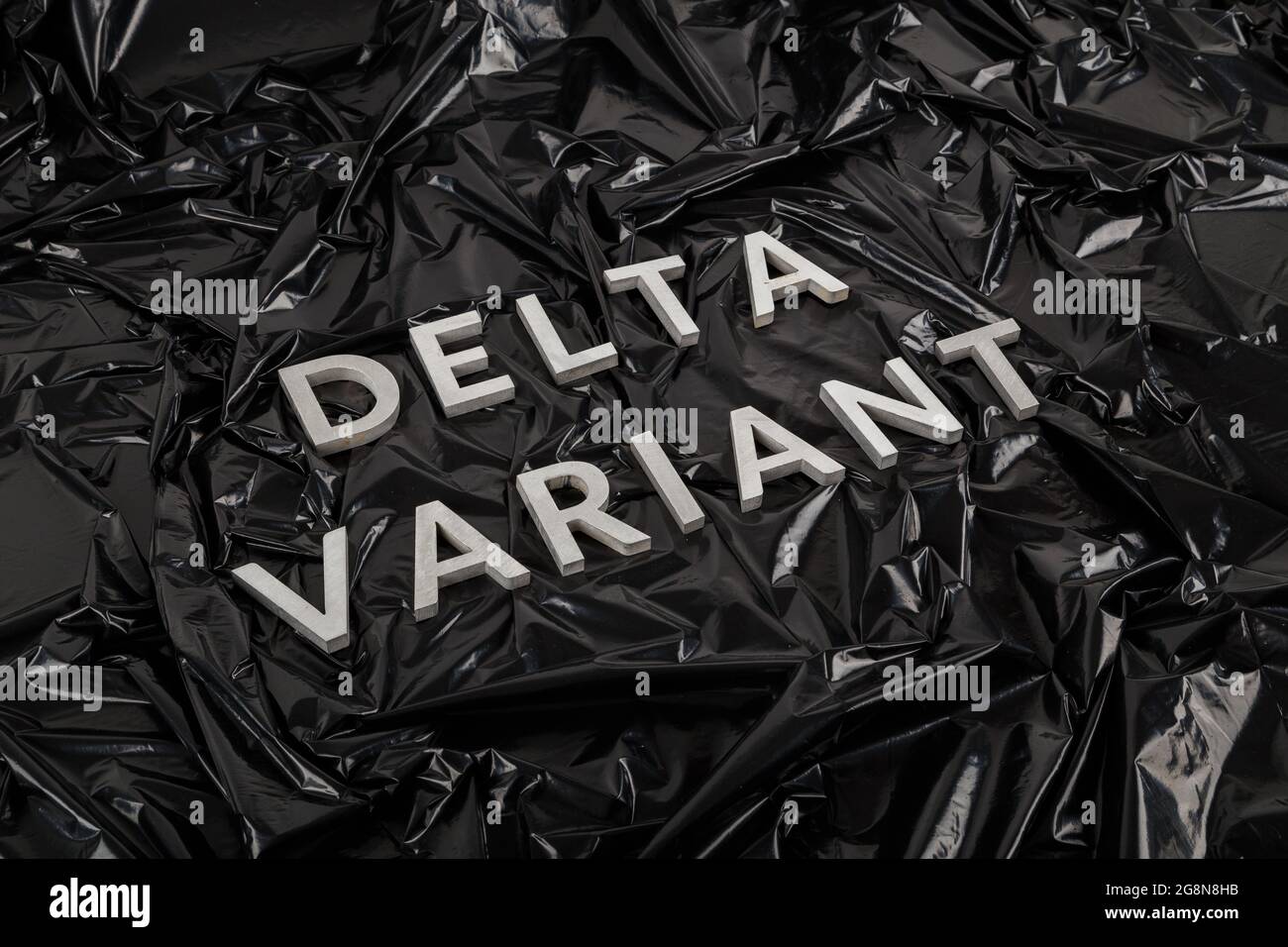 words delta variant laid with silver metal letters on crumpled black ...