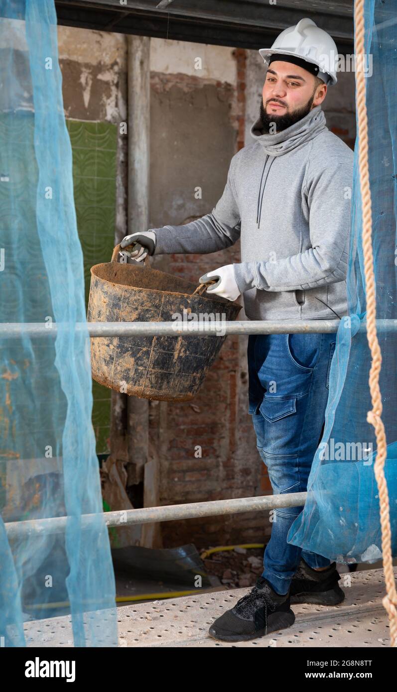 Contractor carrying bucket with cement mortar Stock Photo - Alamy